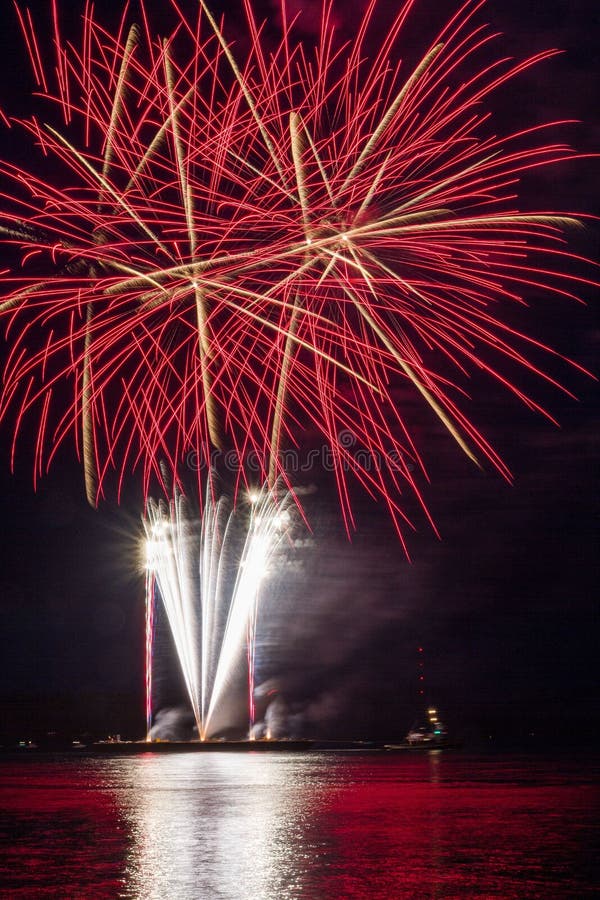 Vertical Shot of Bright Red and White Fireworks Display Over the Water ...