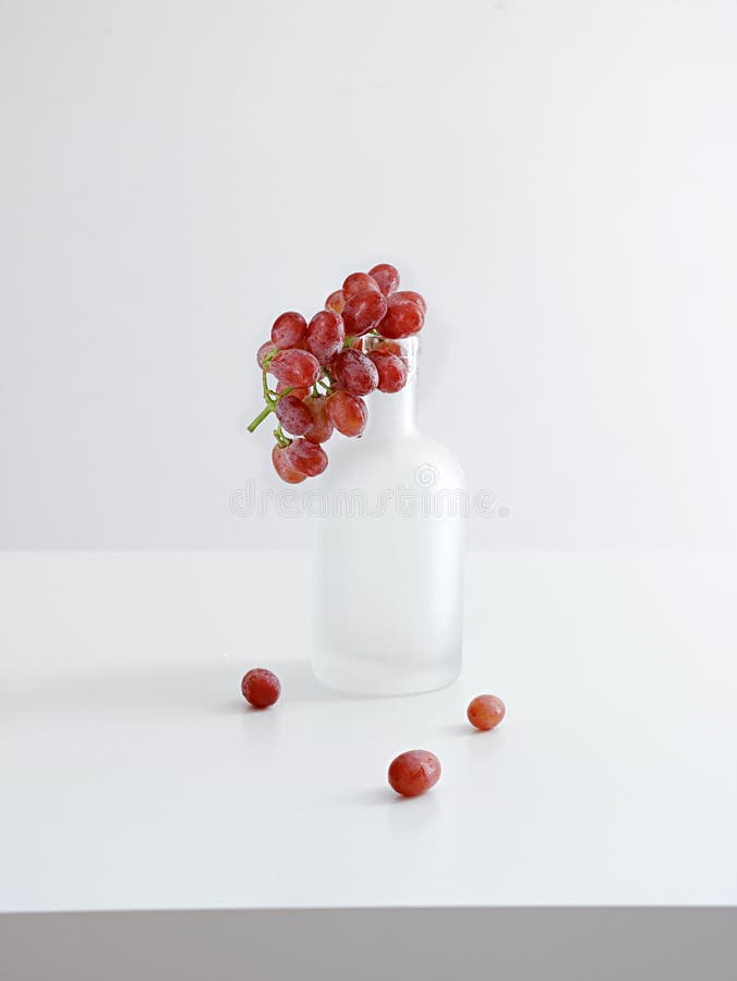 Vertical Shot of a Bunch of Red Grape on a Glass Bottle on White ...