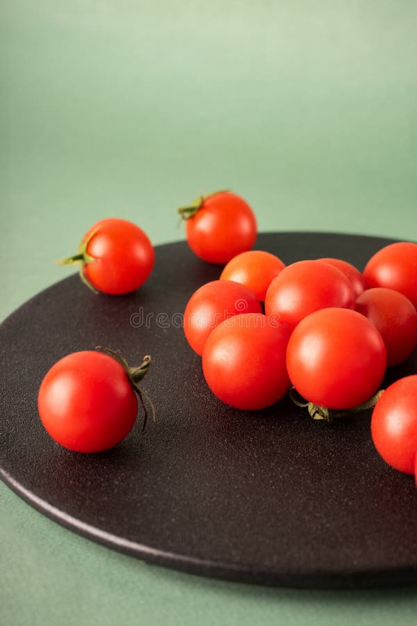 Vertical Shot of Bunch of Small Tomatoes on Black Plate in Green ...