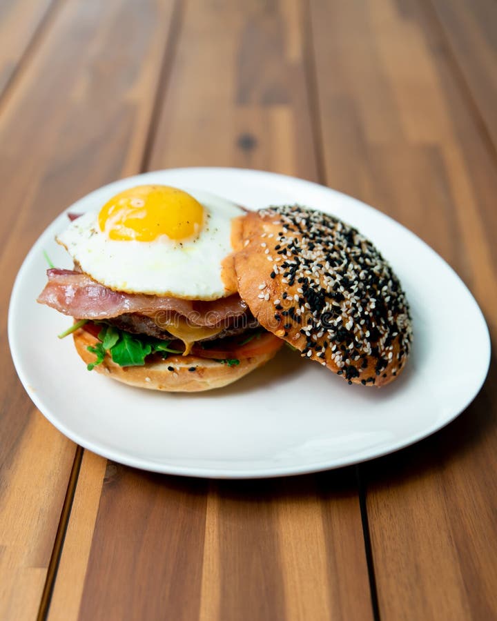 Vertical Shot of a Burger with Fried Eggs and Bacon on a White Plate ...