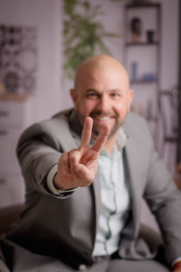 Vertical Shot of a Businessman Showing Peace Sign and Smiling Stock ...