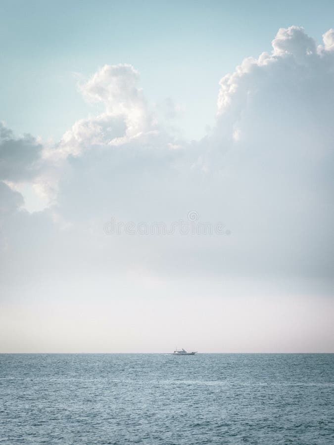 Vertical Shot of a Calm Sea with a Boat in the Horizon Stock Photo ...