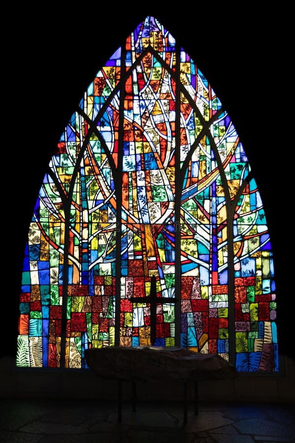 Vertical Shot Of A Christian Cross With A Stained Glass Window In The