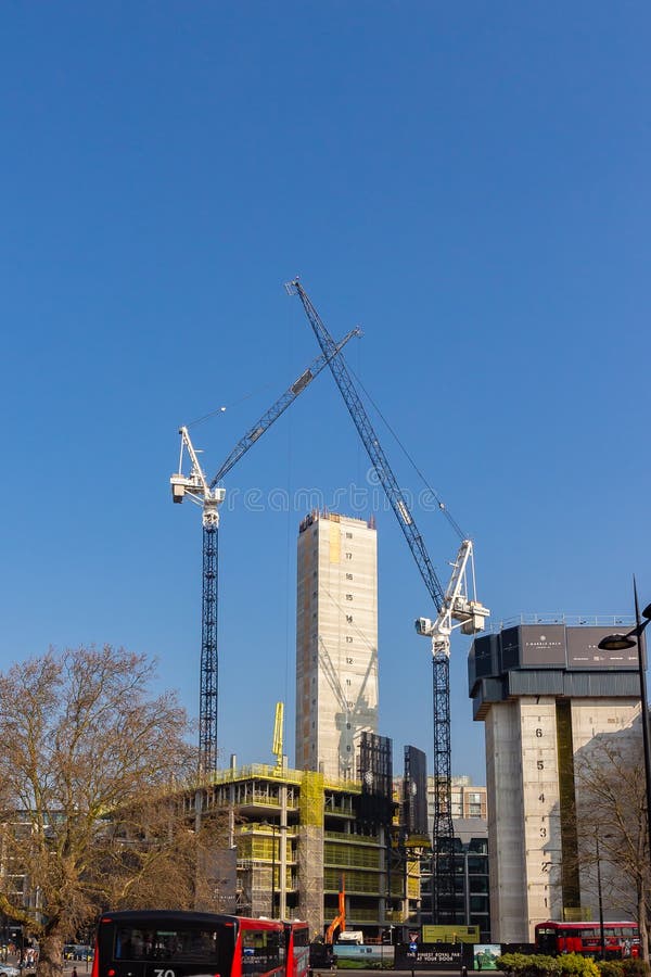 Vertical Shot of a City View with Two Tall Construction Cranes Working ...