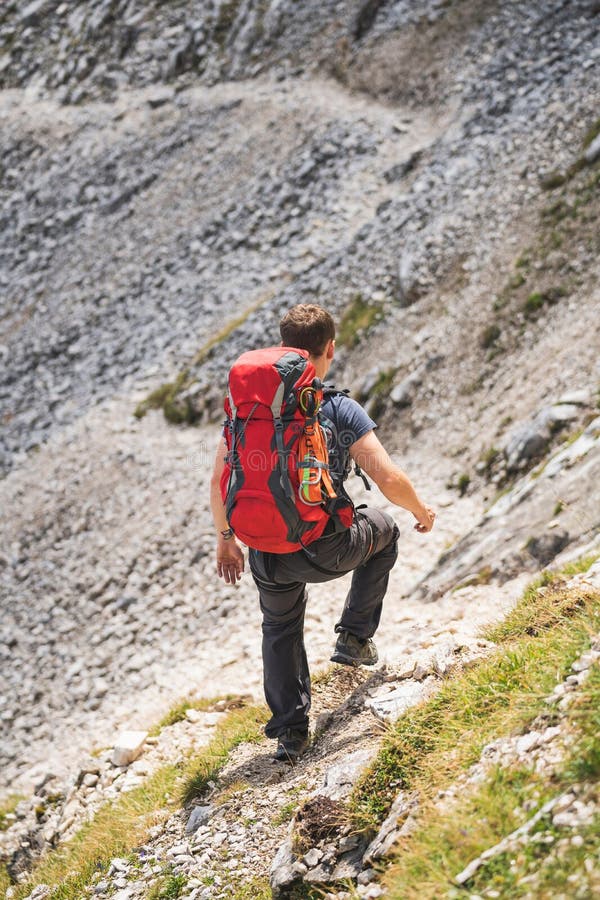 Vertical Shot of a Climber in a Red Backpack and Going Up the Hill ...
