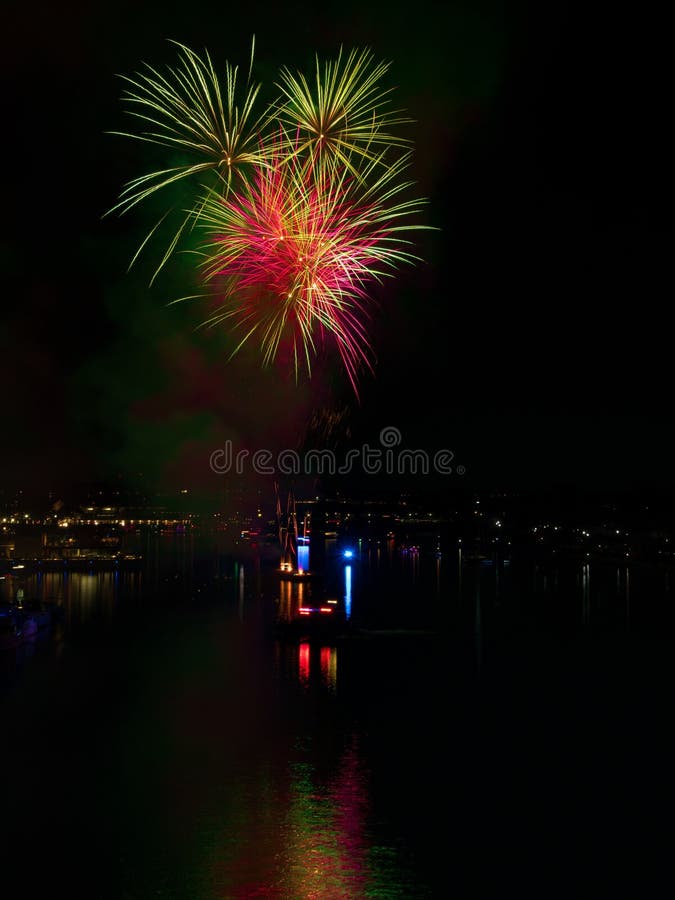 Vertical Shot of Colorful Fireworks Reflecting on Water in a Town ...