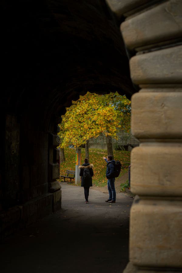 Vertical Shot of a Couple Walking through a Stone Tunnel in the Fall ...