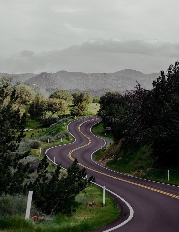 Vertical Shot of a Curvy Road with Forested Mountains in the Background ...