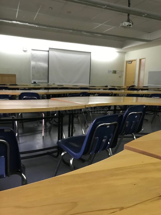 Vertical Shot of an Empty Classroom with Blue Chairs and Wooden Tables ...