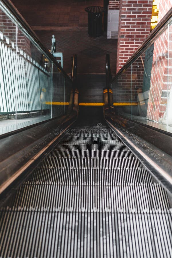 Vertical Shot of an Escalator Going Down through a Building with Brick ...