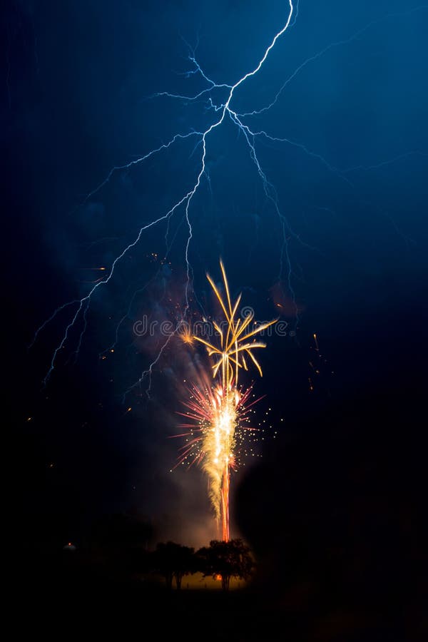 Vertical Shot of Fireworks Exploding in a Night Sky while Lightning ...