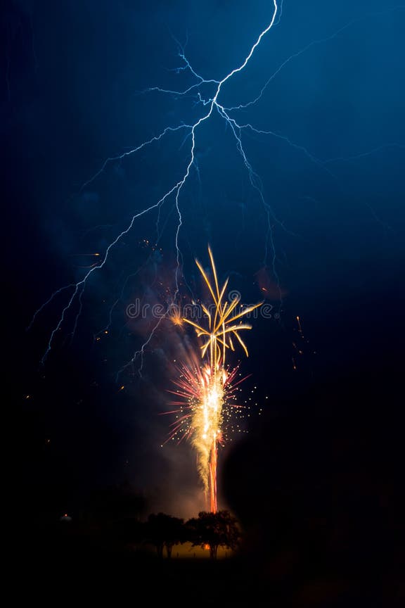 Vertical Shot of Fireworks Exploding in a Night Sky while Lightning ...