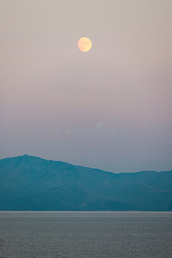 Vertical Shot of a Full Moon Above the Sea and Mountains Stock Image ...