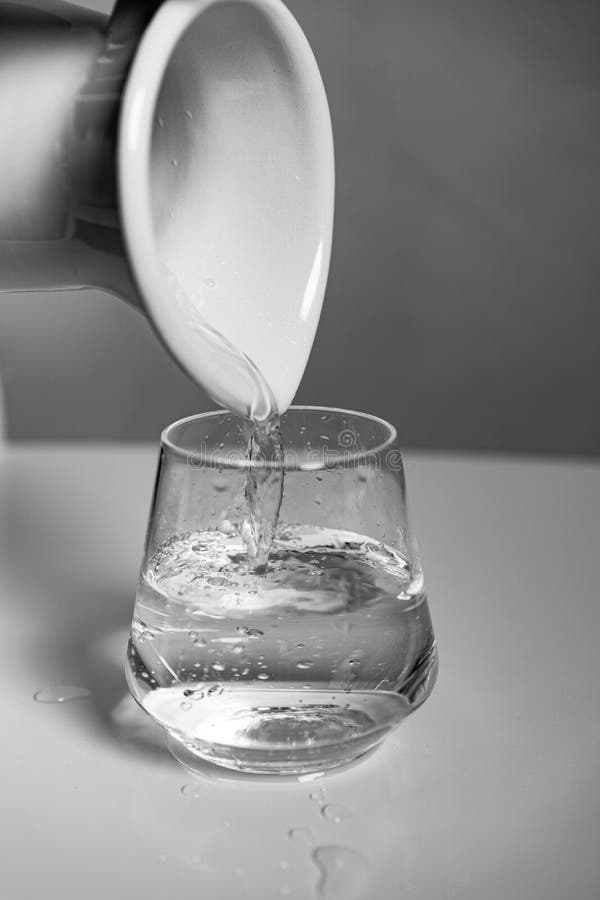 Vertical Shot of a Glass Being Filled with Water from a Ceramic Pitcher ...