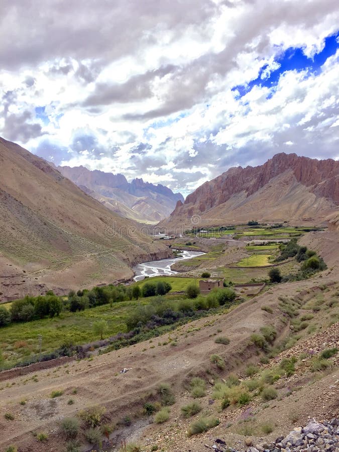 Vertical Shot of a Greenery at a Valley Surrounded by Bare Mountains in ...