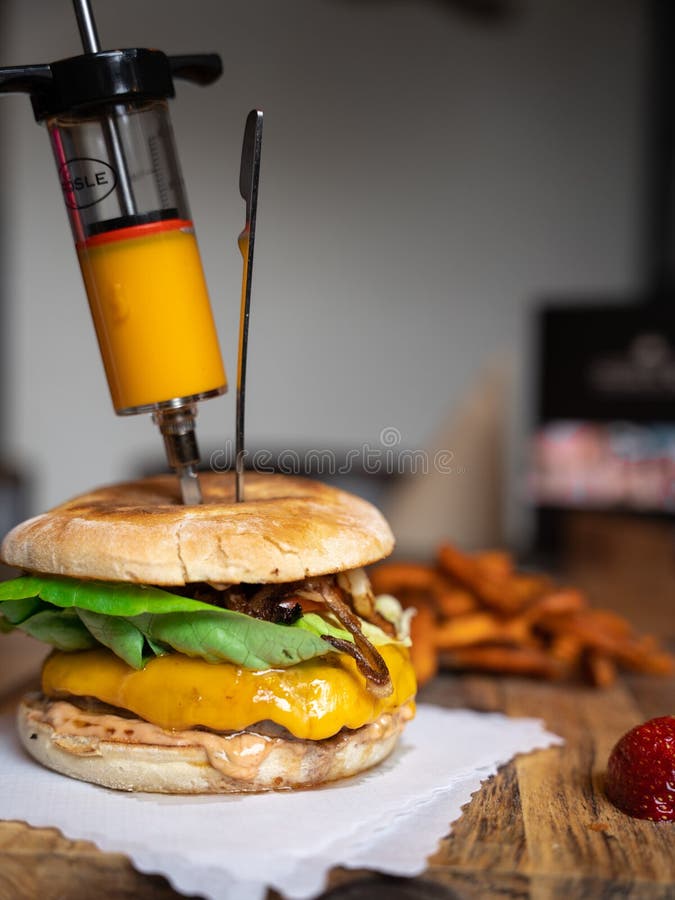 Vertical Shot of a Hamburger with a Syringe of Sauce Going Inside it ...