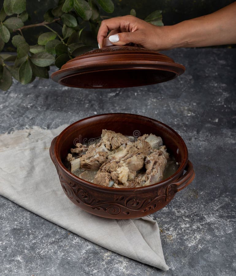 Vertical Shot of a Hand Opening a Gourmet Pot of Lamp Soup on a Granite ...