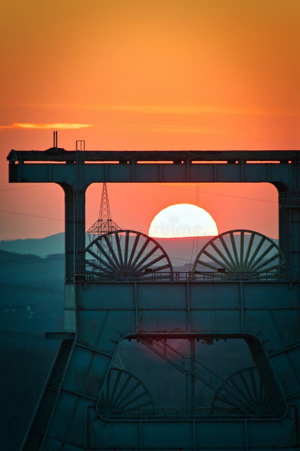 Vertical Shot of a Headframe Tower with a Golden Sun Setting in the ...