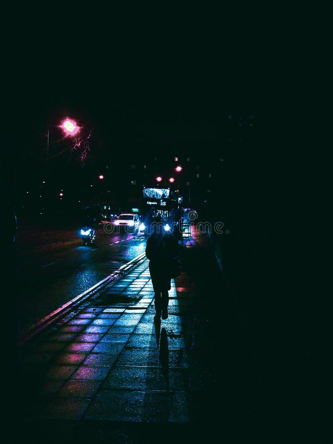 Vertical Shot of a Human Silhouette Walking Along an Urban Sidewalk ...