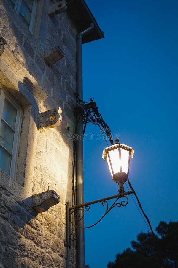 Vertical Shot of Illuminated Light Lantern on an Old Building Outside ... Vertical Shot of Illuminated Light Lantern on an Old Building Outside ...