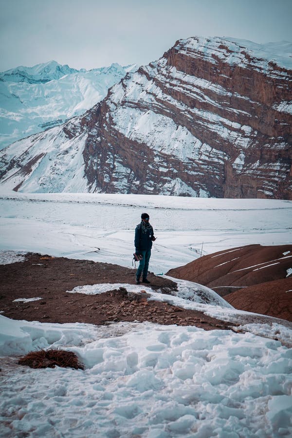 Vertical Shot of a Lonely Person Walking in Snow-covered Mountains ...