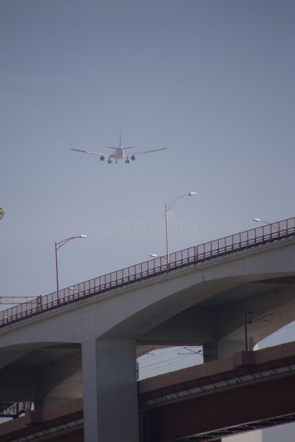 Vertical Shot of a Low Flying Airplane Over a Bridge Stock Photo ...