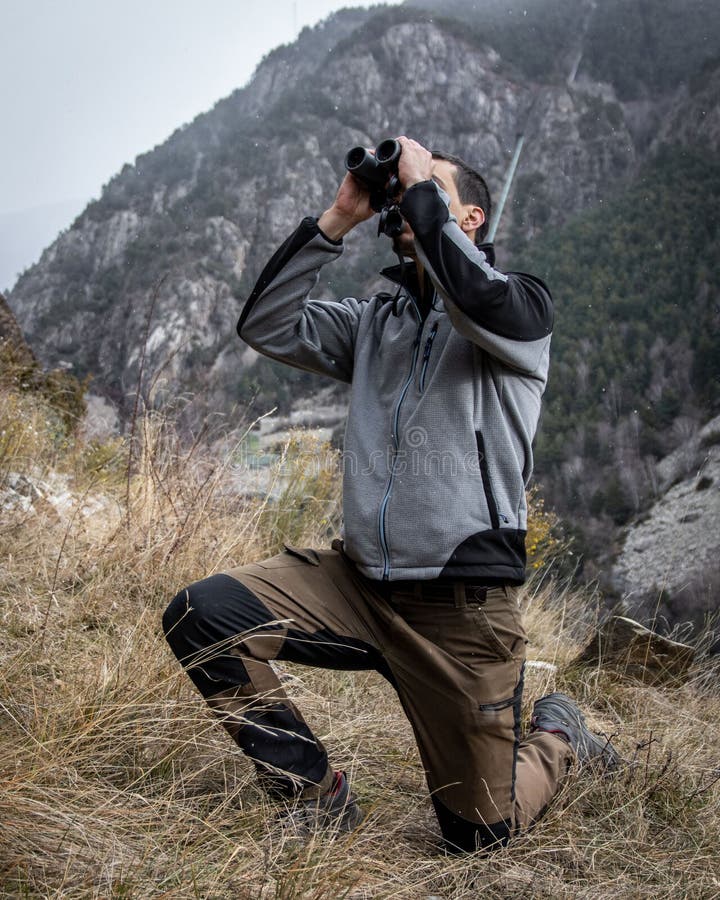 Vertical Shot of Male Hiker Looking Up with Binoculars Kneeling on the ...