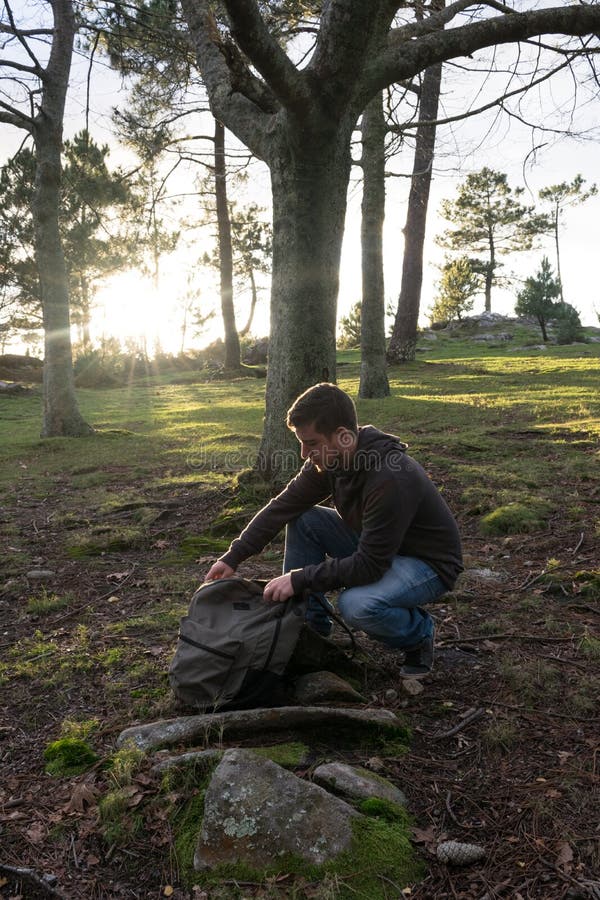 Vertical Shot of a Male Zipping His Backpack while Squatting in the ...