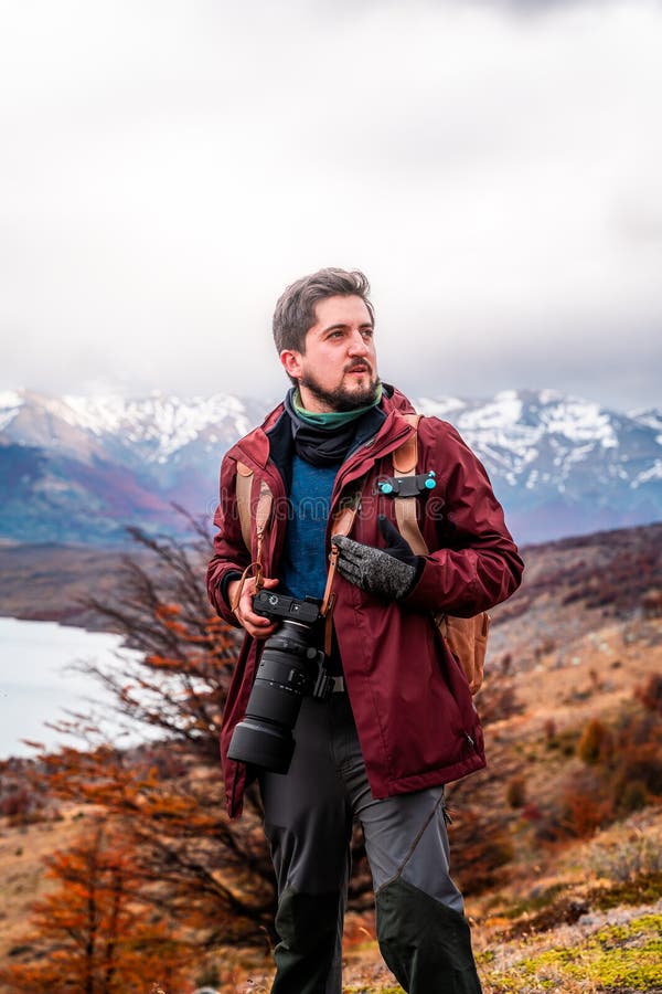 Vertical Shot of a Man with a Camera on a Mountaintop, Surrounded by ...