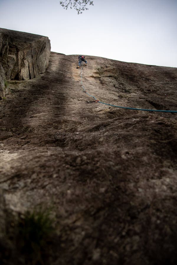 Vertical Shot of a Man Climbing a Rock with a Rope Stock Photo - Image ...