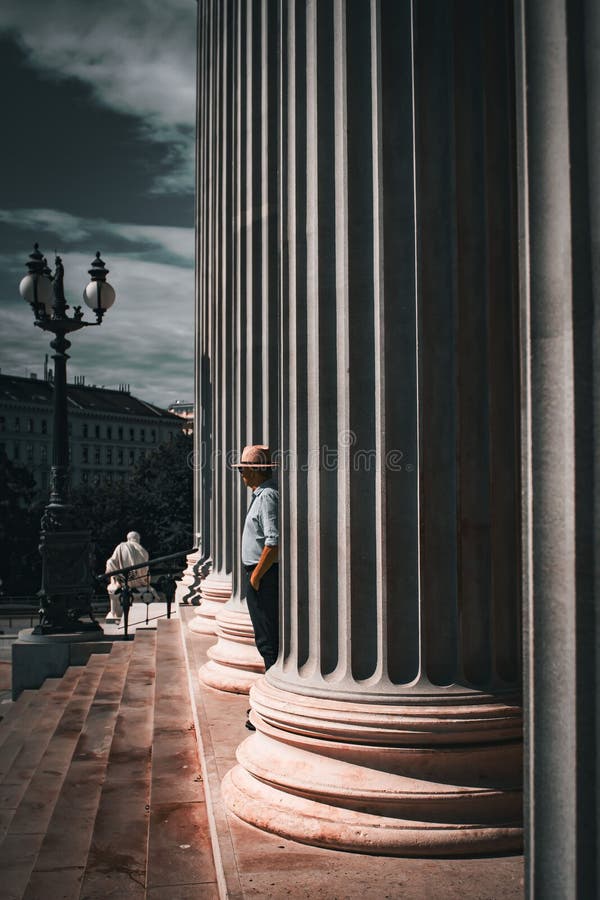 Vertical Shot of a Man in Hat Standing between Columns of an Old High ...
