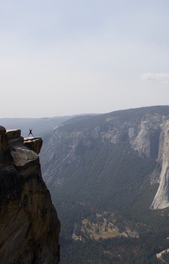 Vertical Shot of a Man Standing on the Edge of a Rock Stock Photo ...
