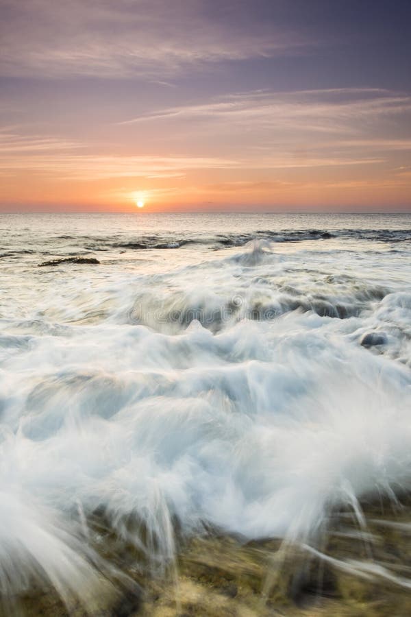Vertical Shot of the Mesmerizing Foamy Ocean Waves Under a Peachy ...