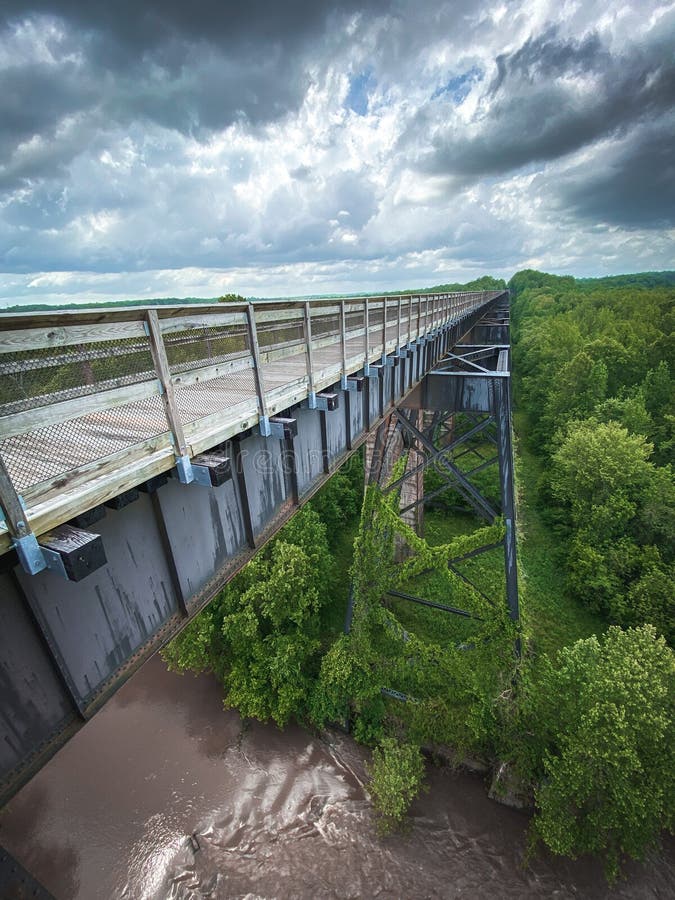 Vertical Shot of a Metal Bridge Over the Muddy River and Green Trees ...