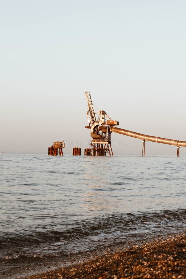 Vertical Shot of a Metal Crane Machine in the Water with a Clear Sky in ...