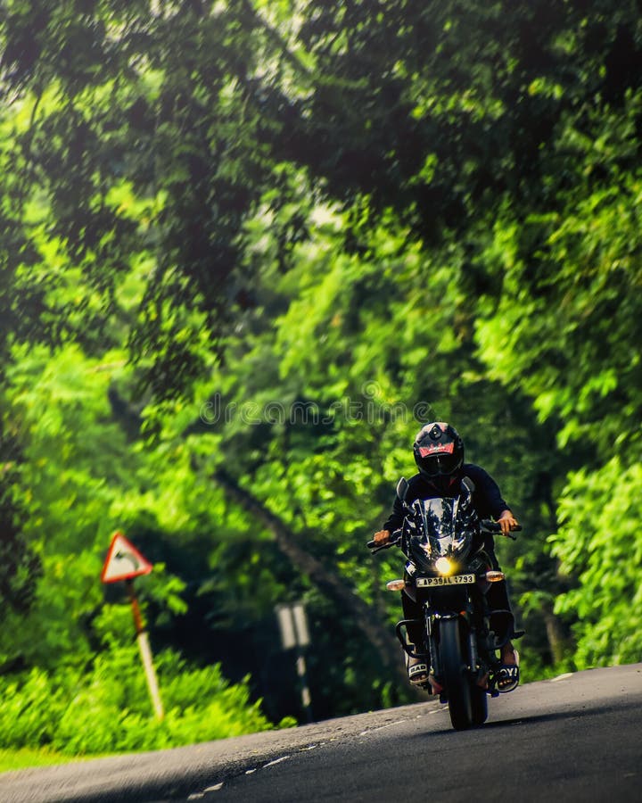 Vertical Shot of a Motorcyclist Riding on a Road Surrounded by Trees ...