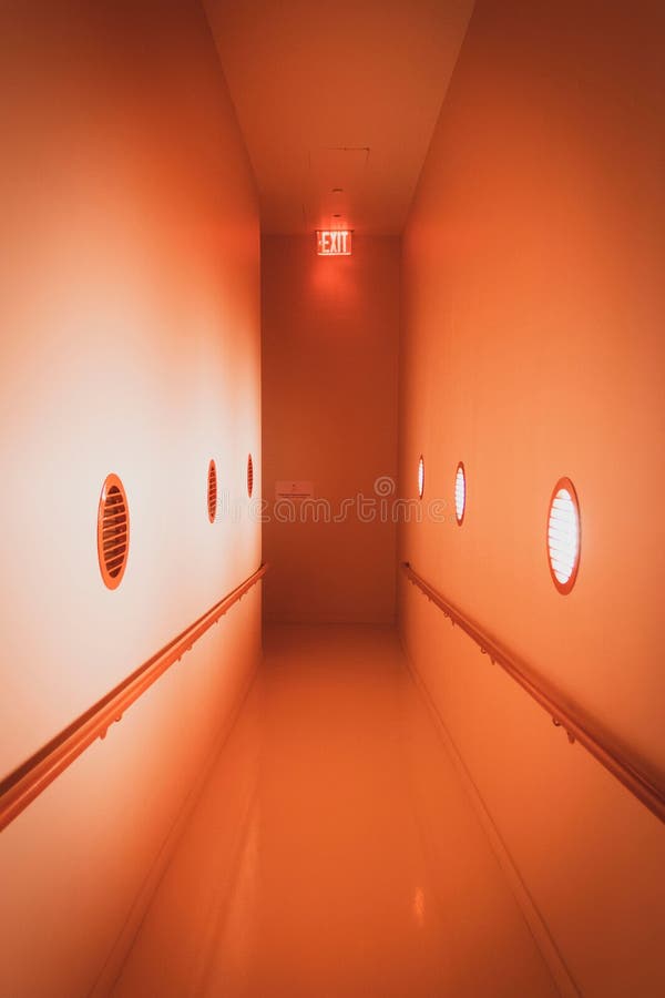 Vertical Shot of a Narrow Corridor with an Exit Sign and Orange Lights ...