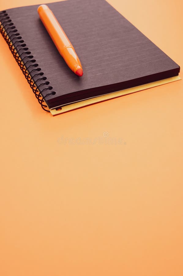 Vertical Shot of a Notebook and an Orange Marker on an Orange Surface ...