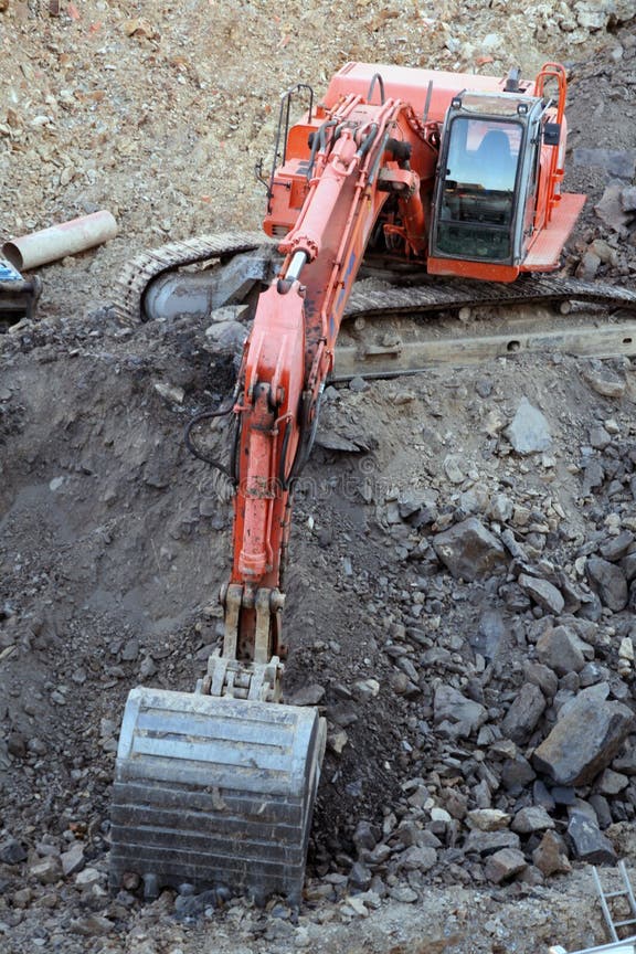 Vertical Shot of an Orange Excavator Digging in a Hole Stock Photo ...