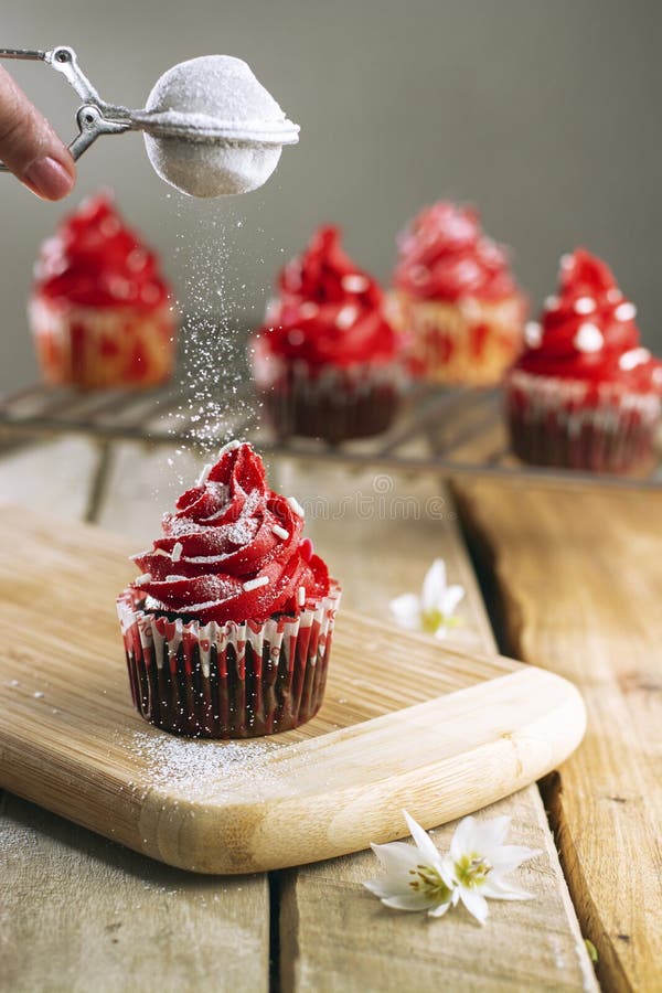 Vertical Shot of a Person Adding Sugar Powder on a Cupcake with Red ...