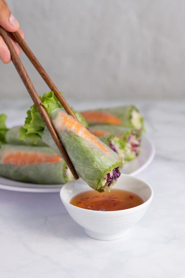 Vertical Shot of a Person Dipping a Vietnamese Spring Roll into Fish ...