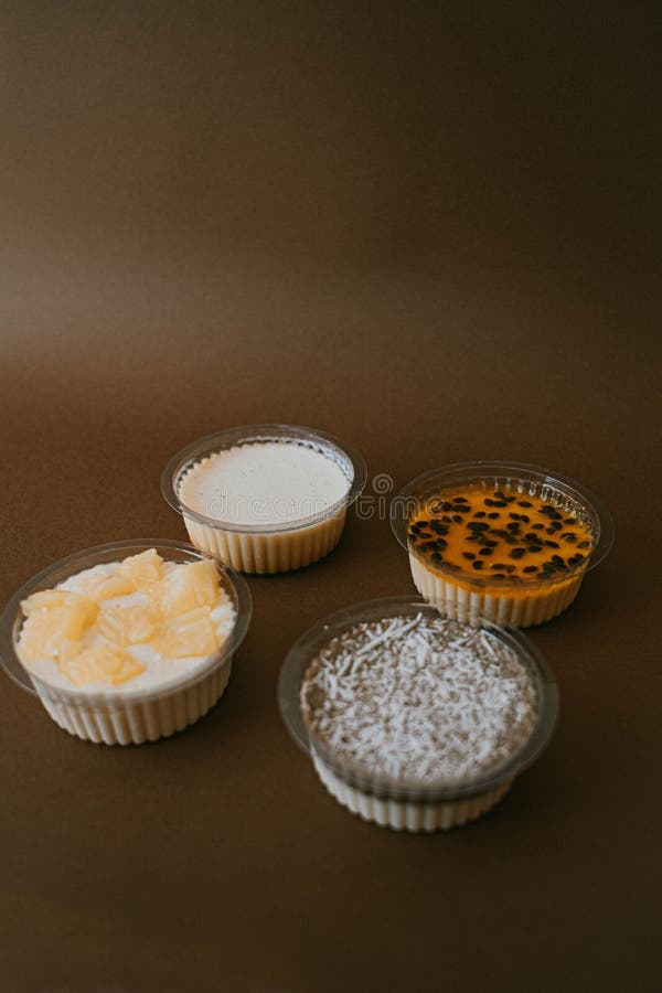 Vertical Shot of Plastic Bowls of Various Creamy Pudding on a Brown ...
