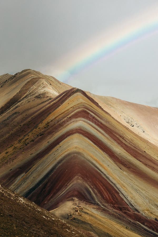 Vertical Shot of the Rainbow Mountain in Peru with a Rainbow in the Sky ...