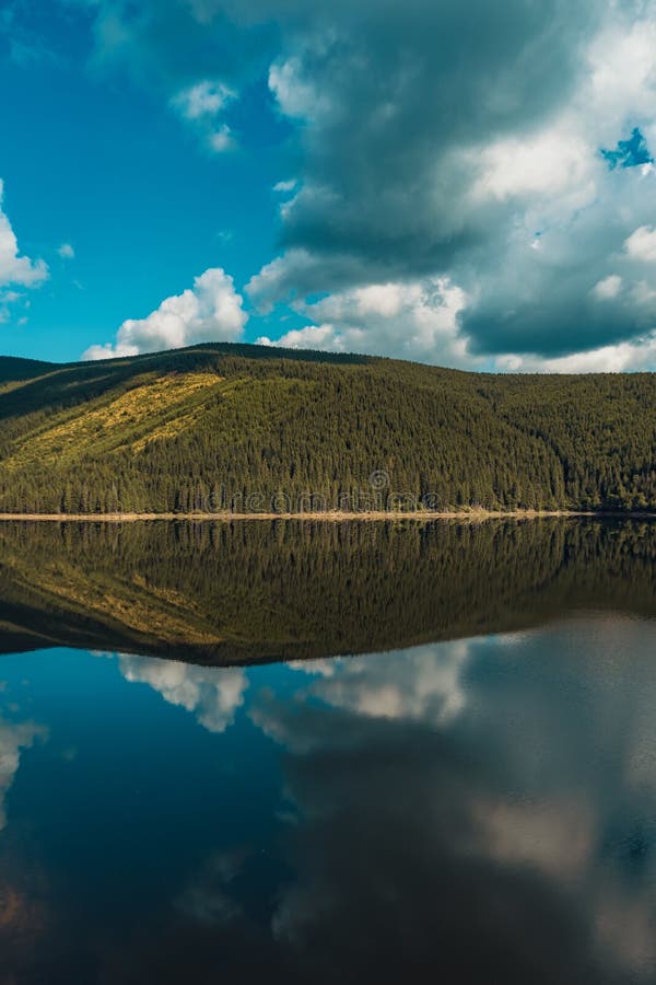 Vertical Shot of the Reflection of a Hill and the Beautiful Sky in the ...