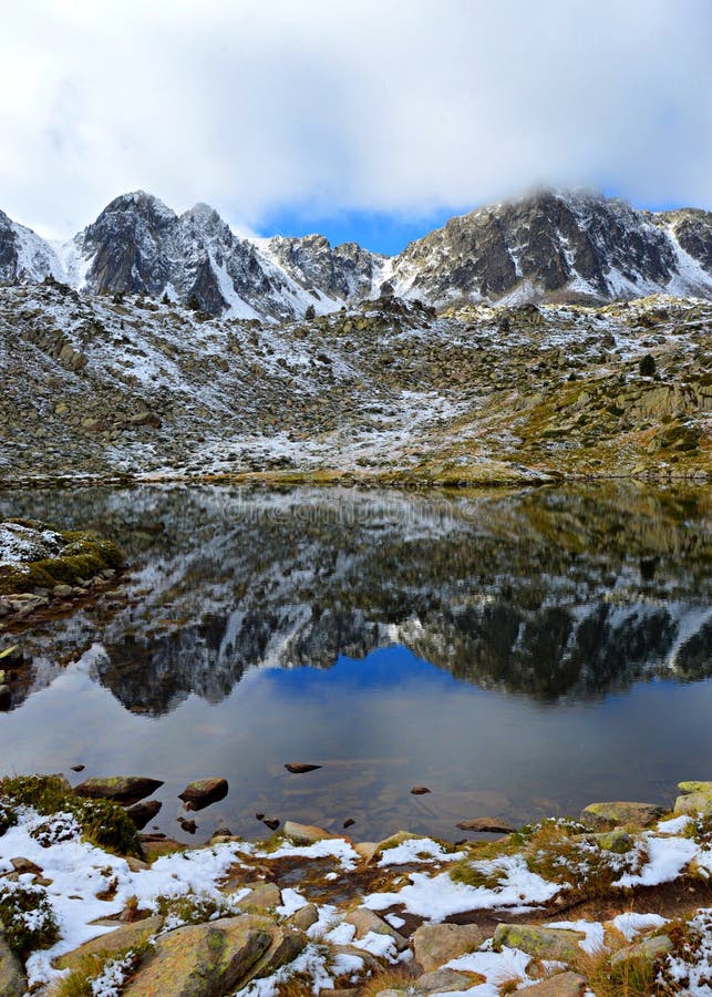 Vertical Shot of a Rocky Snow-covered Mountains with a Reflection on a ...