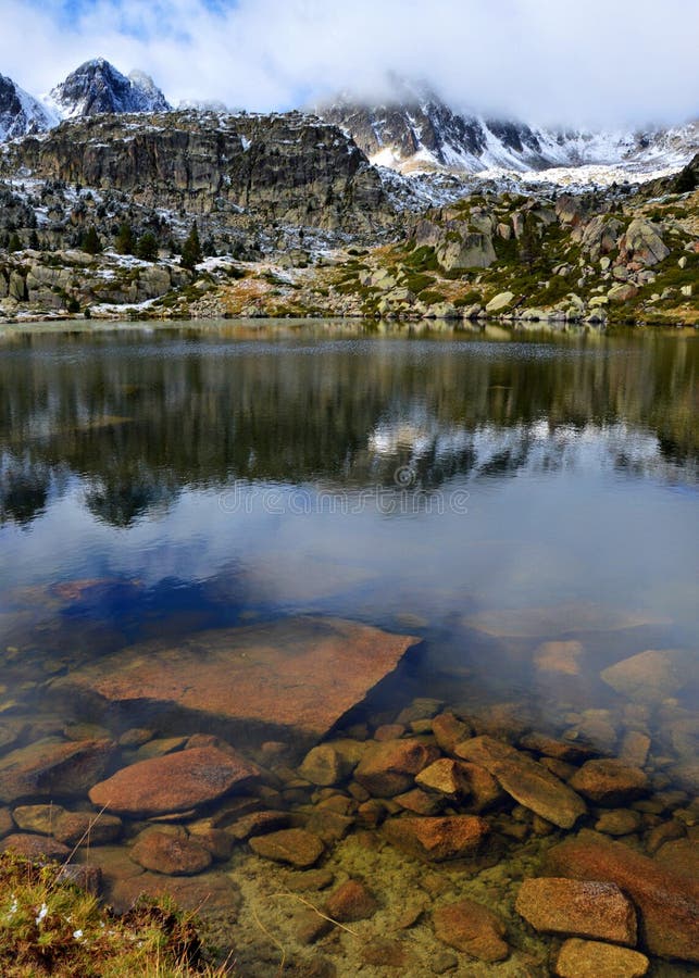 Vertical Shot of a Rocky Snow-covered Mountains with a Reflection on a ...