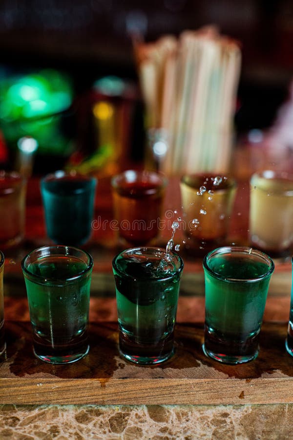 Vertical Shot of a Row of Splashing Green Alcohol Shots at a Bar Stock ...