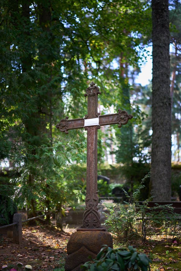 Vertical Shot of a Rusty Metal Cross with a Facemask Hanging on it in ...