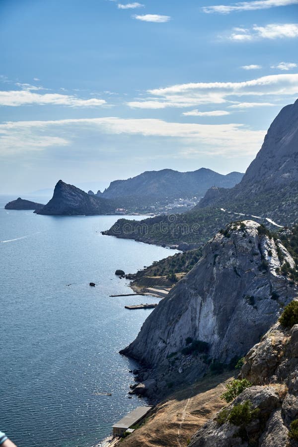 Vertical Shot of the Sea Near Cliffs Under a Blue Cloudy Sky at Daytime ...
