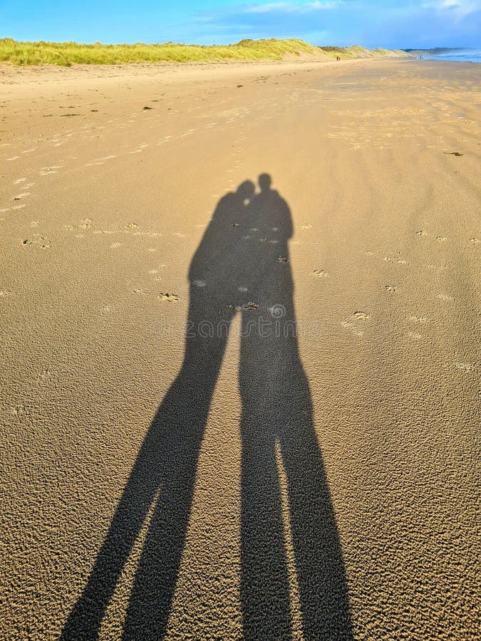Vertical Shot of a Shadow of Two People Standing Next To Each Other on ...